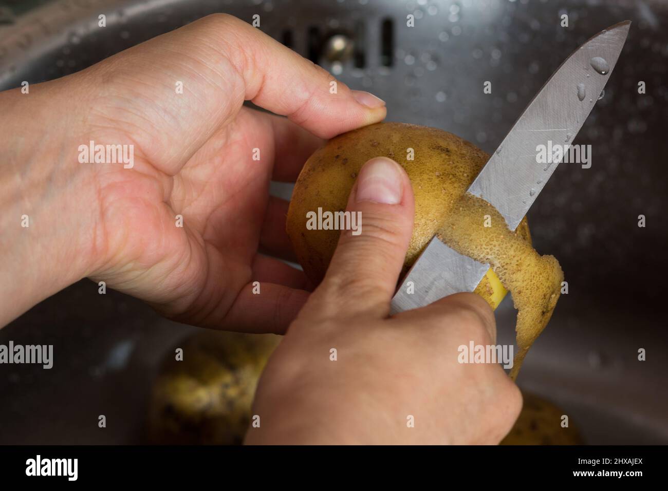 Woman hand peeling potato in the sink with the ordinary knife Stock ...