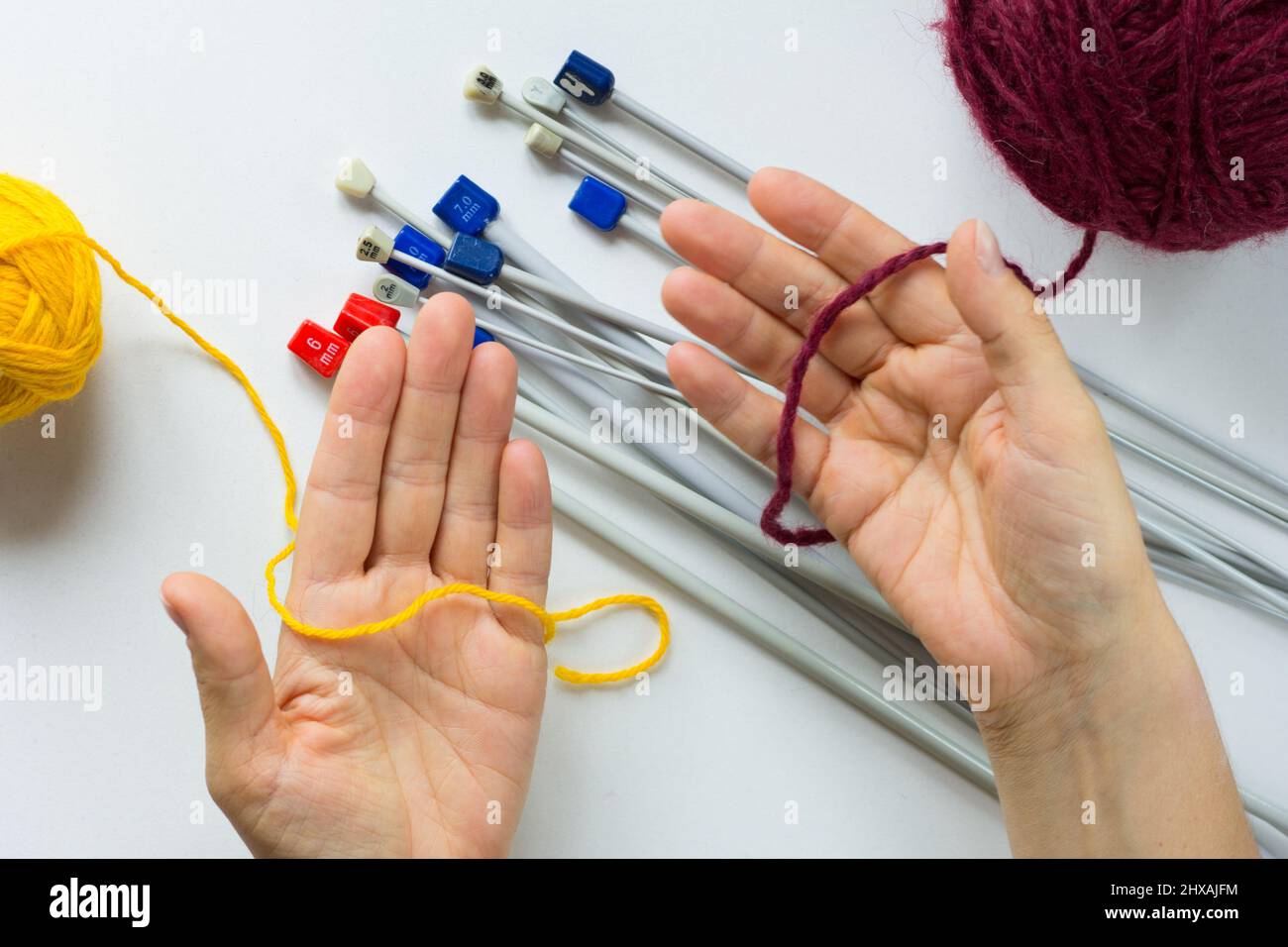 Woman hands holding two different of color and thickness thread to ...