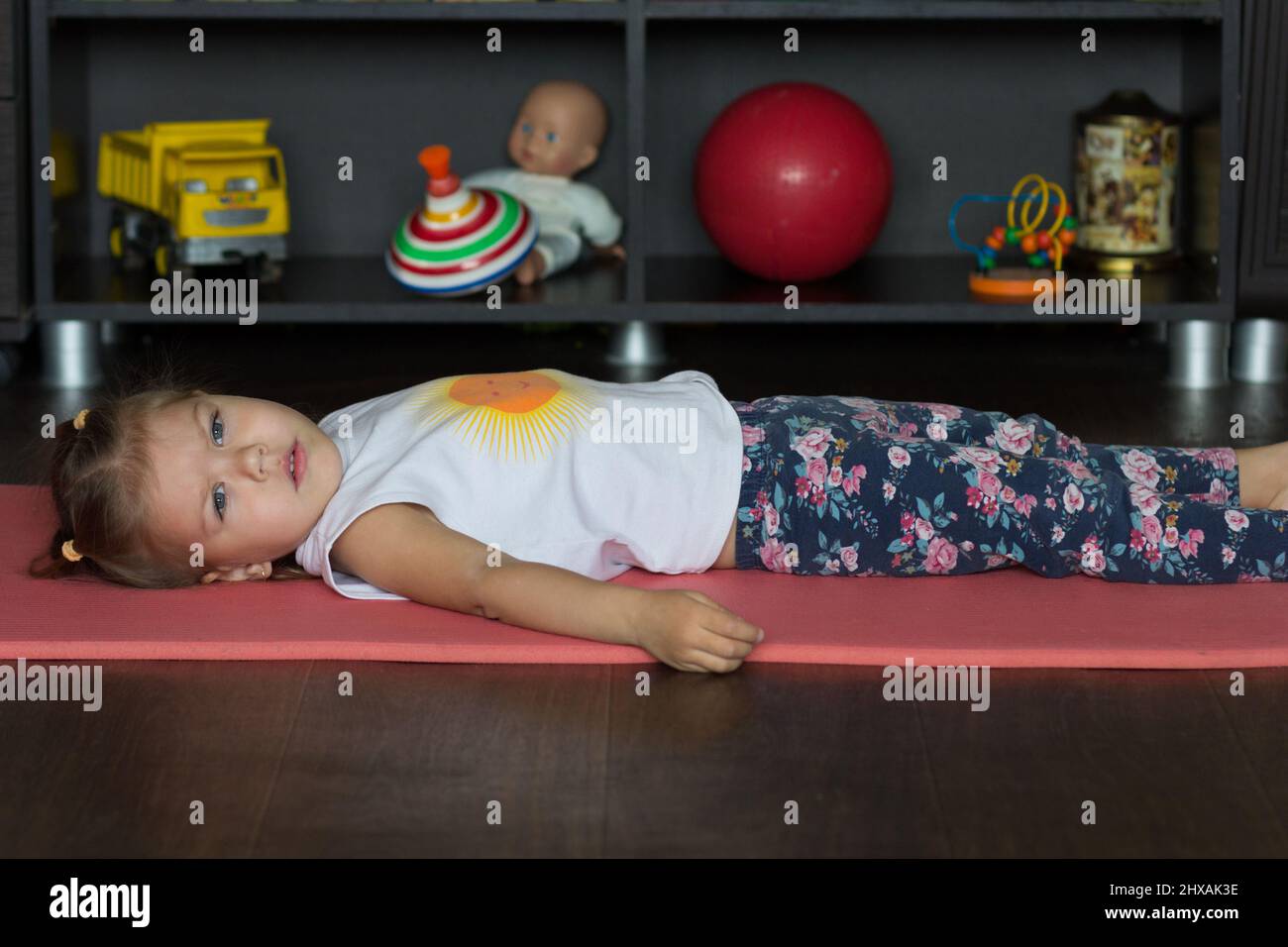 Little girl lying on the mat indoor before physical training Stock ...