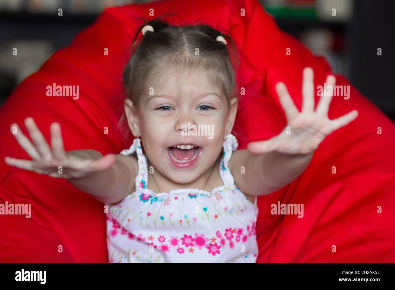 Portrait of cute child stretching hands forward sitting on the red ...