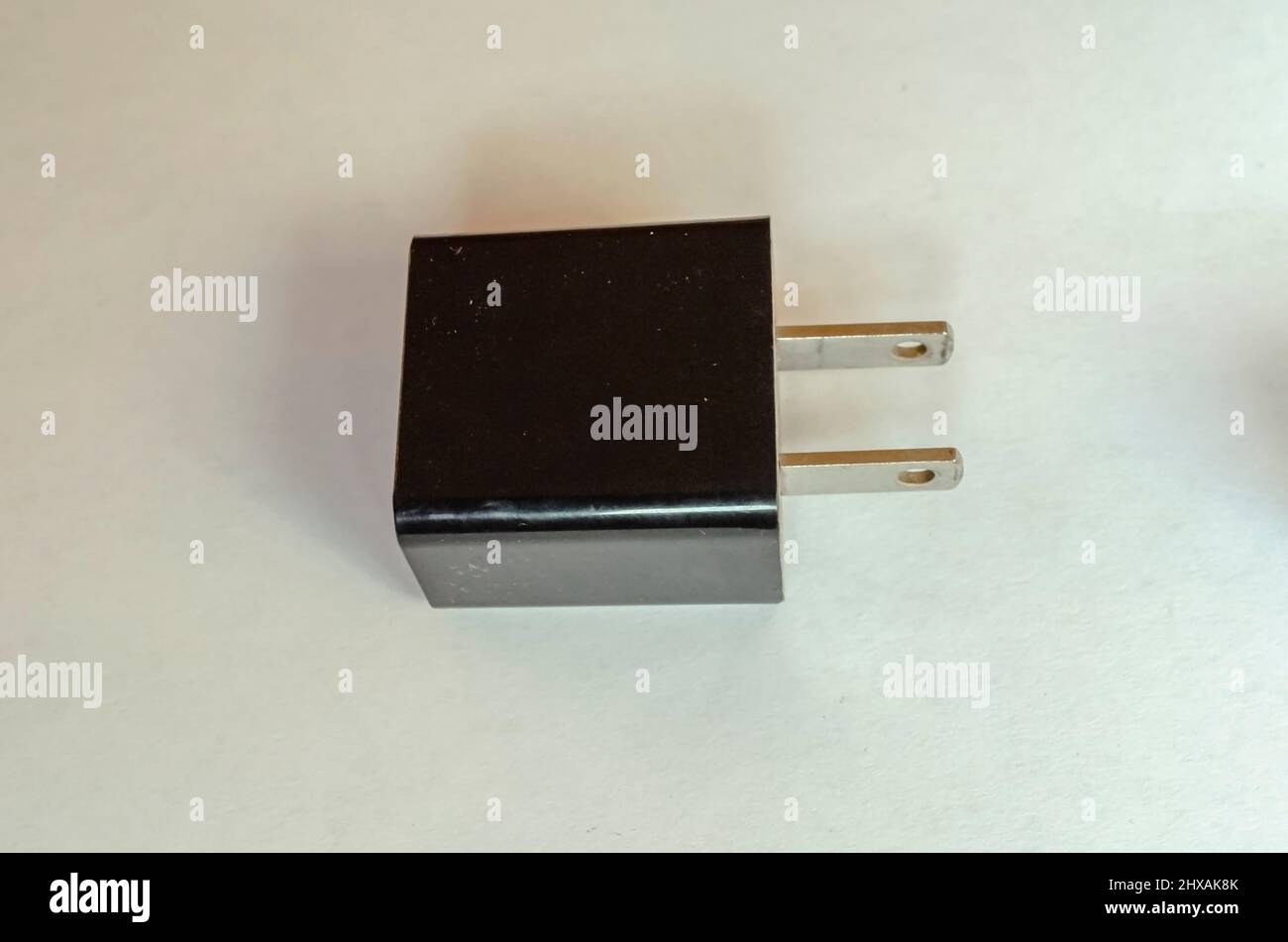 A black wall adopter charger with the two prang wal male plugs turning ...