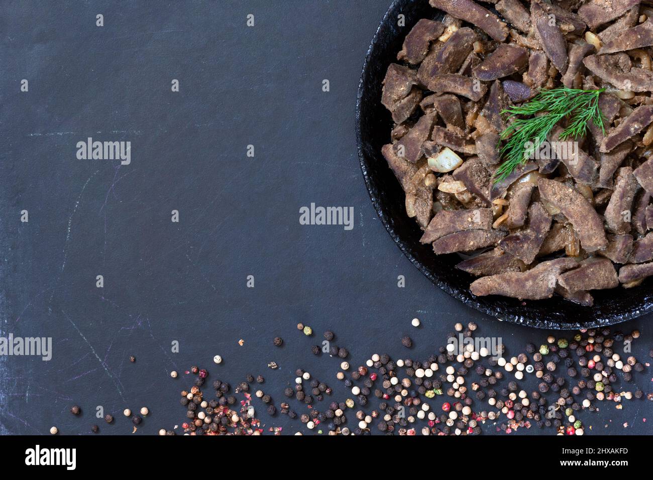Cooked liver on frying pan on black background Stock Photo - Alamy