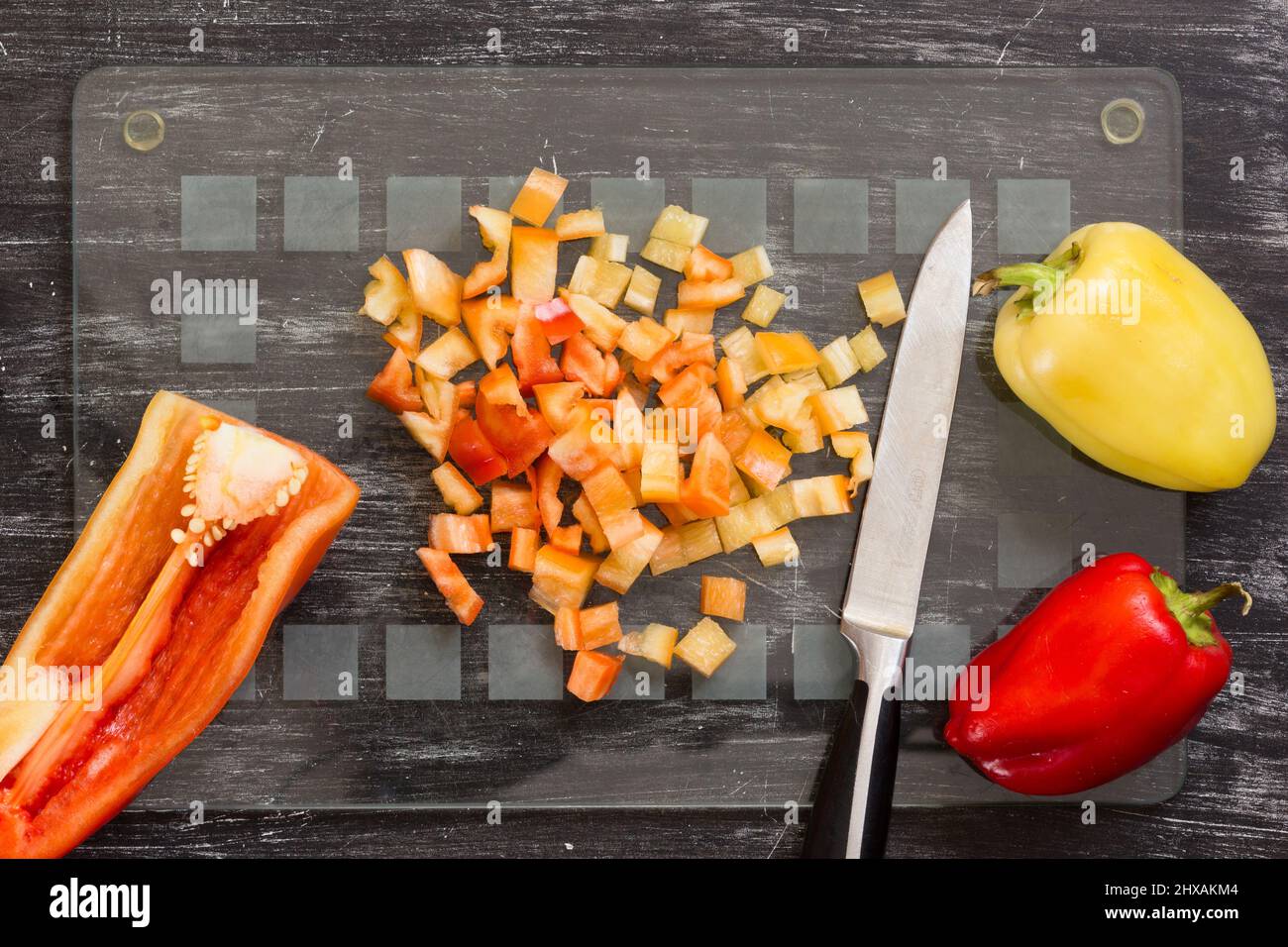 cutted colorful pepper on the glass cut board with knife on the black ...