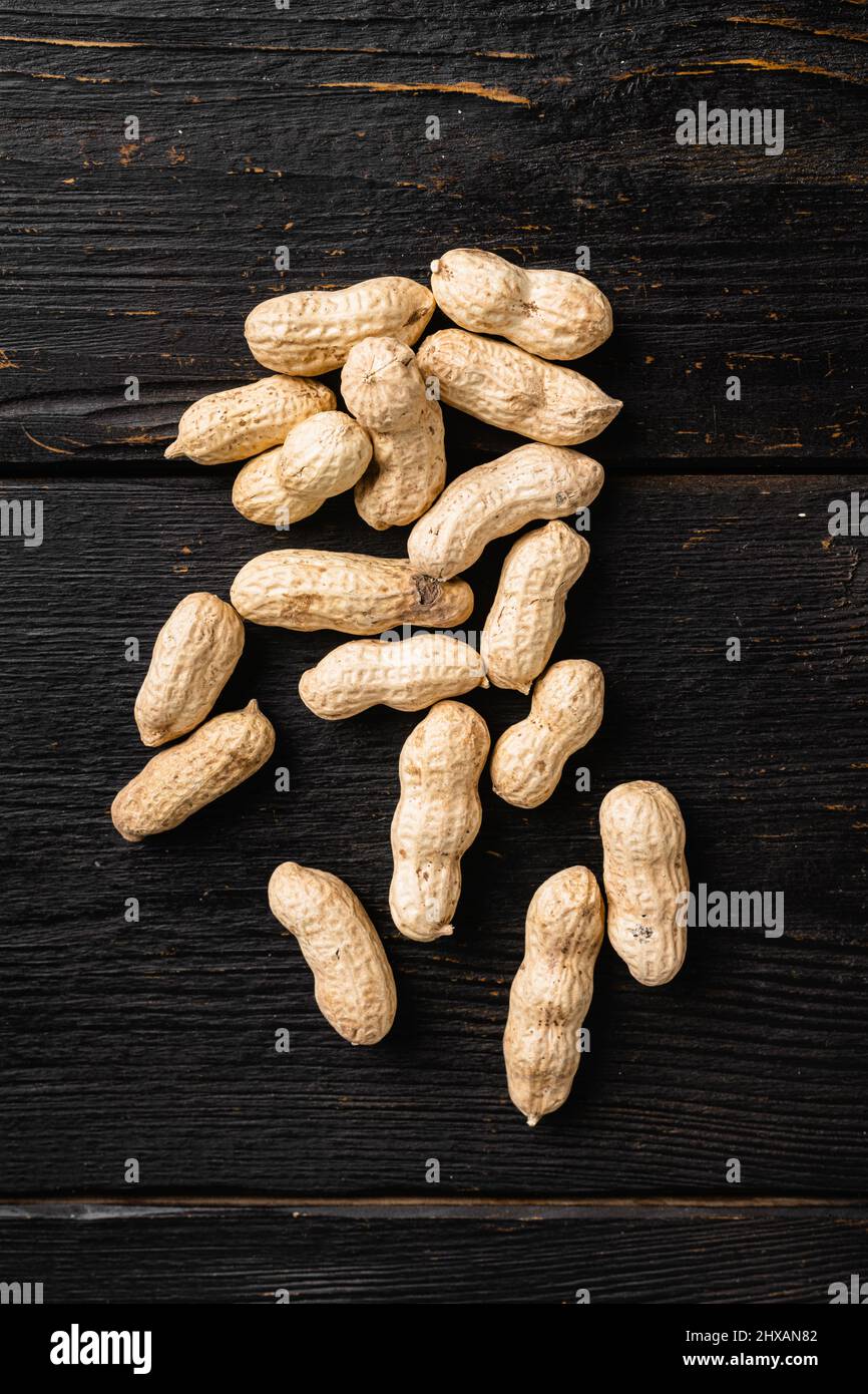 Peanut in a shell set, on black wooden table background, top view flat ...