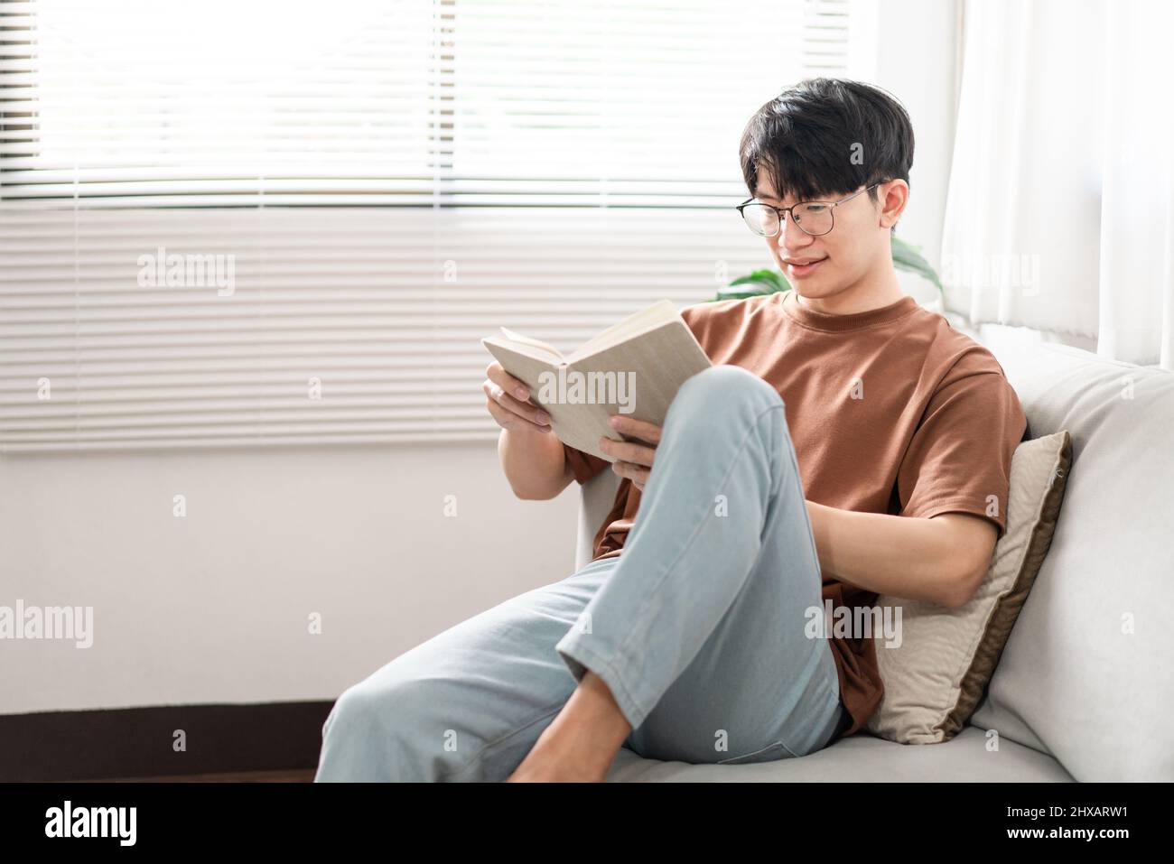 Technology Concept The male with his glasses sitting on the grey sofa ...