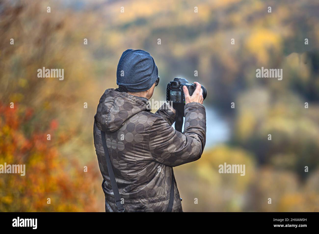 back view of Young photographer takes pictures of autumn landscape ...