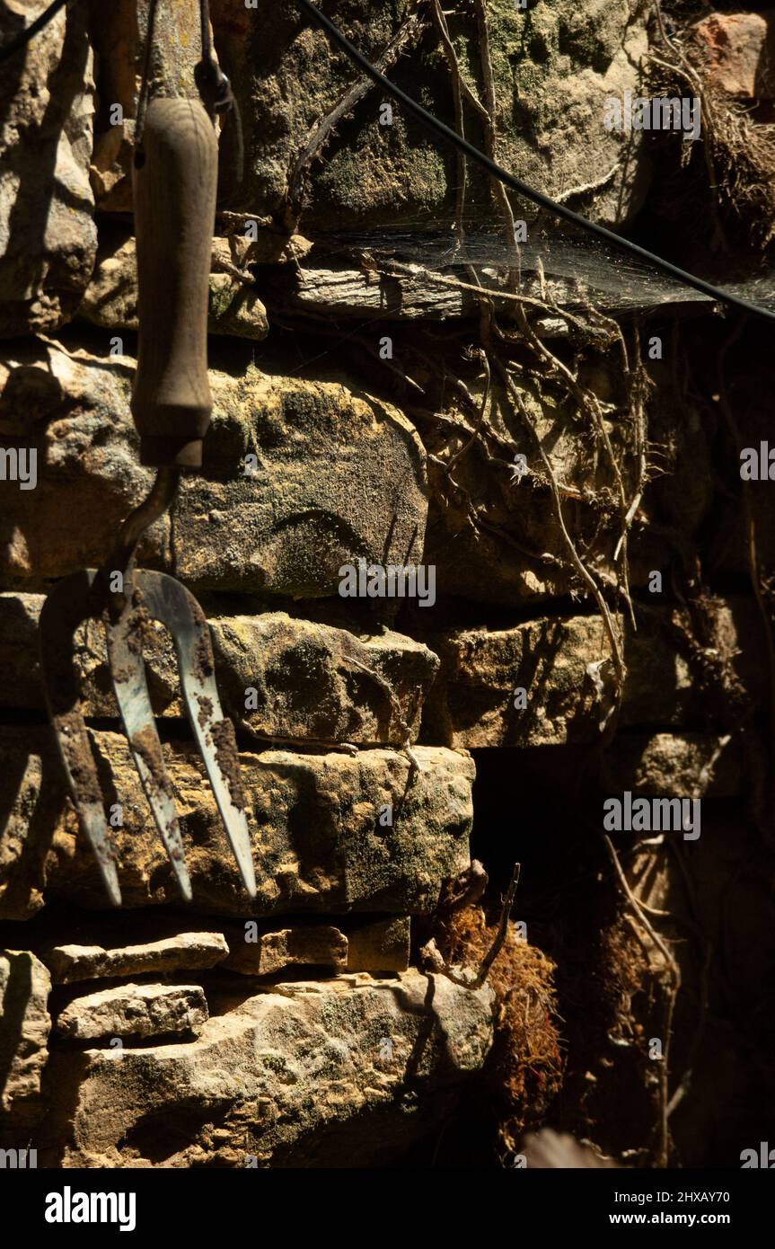 Hand fork hanging from stone wall Stock Photo - Alamy