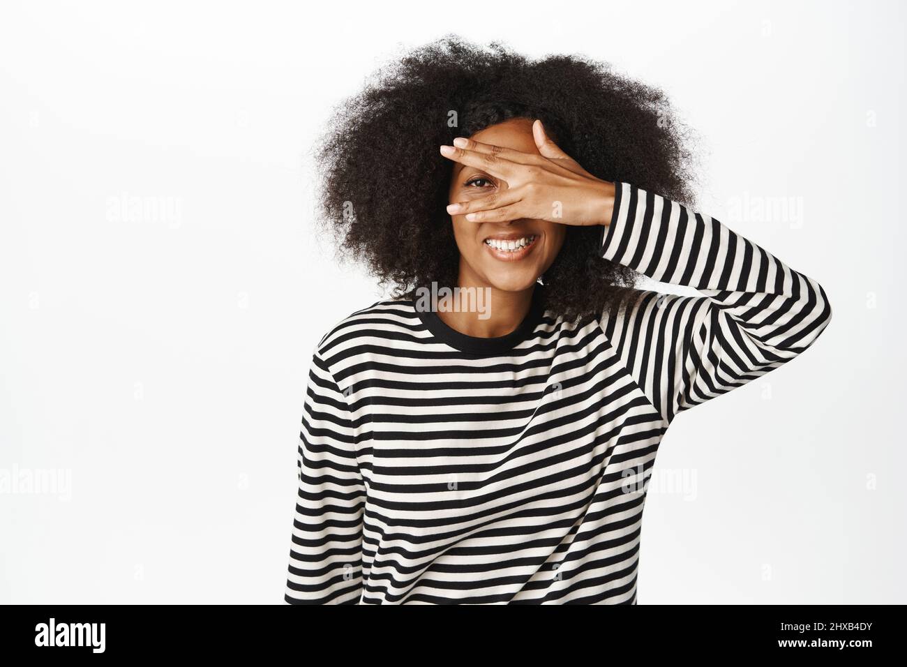 Beautiful african woman peeking through fingers at surprise, smiling ...