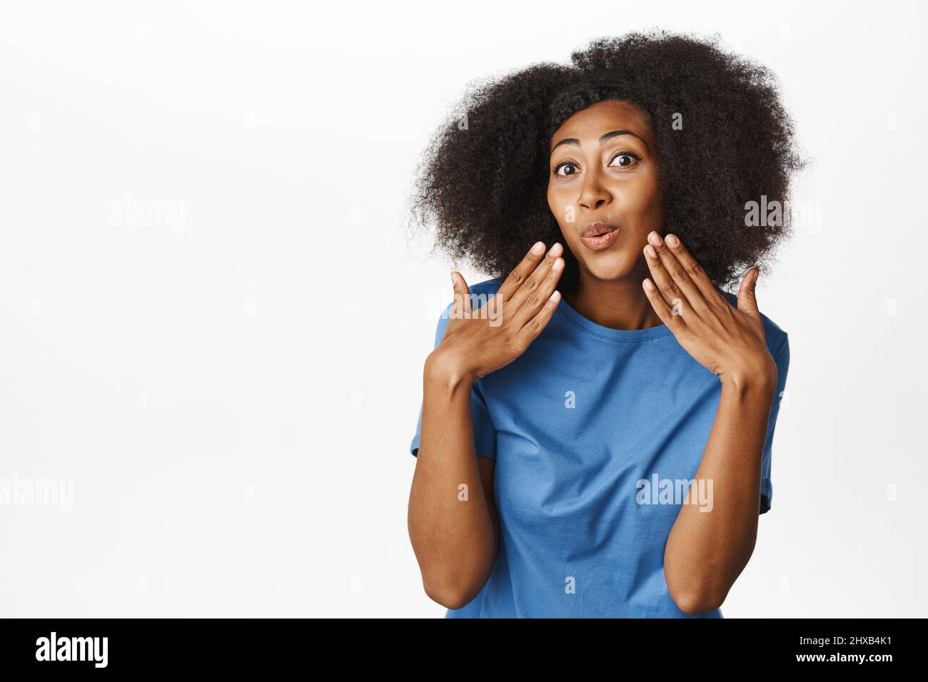 Portrait of coquettish female model with afro hair, chuckle and pucker ...
