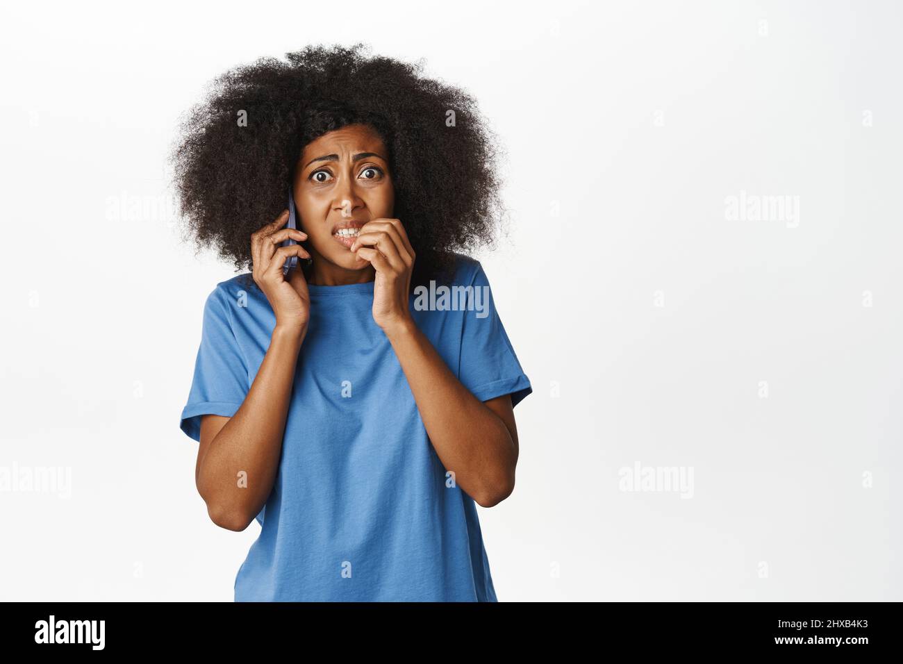 Shocked woman answer phone call, looks scared and worried, standing in ...