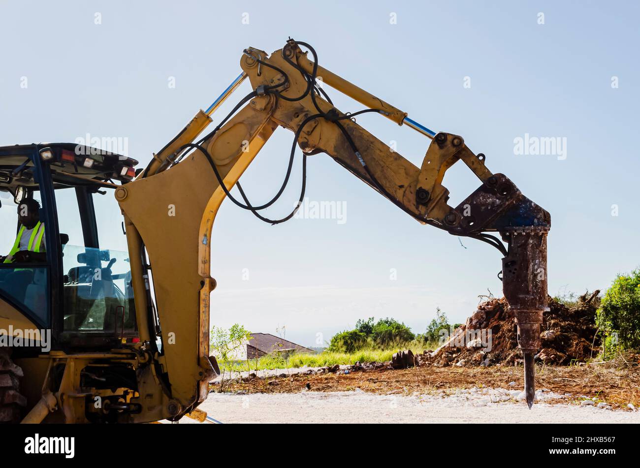 A heavy duty jackhammer attached to the backhoe dipper arm stick is ...