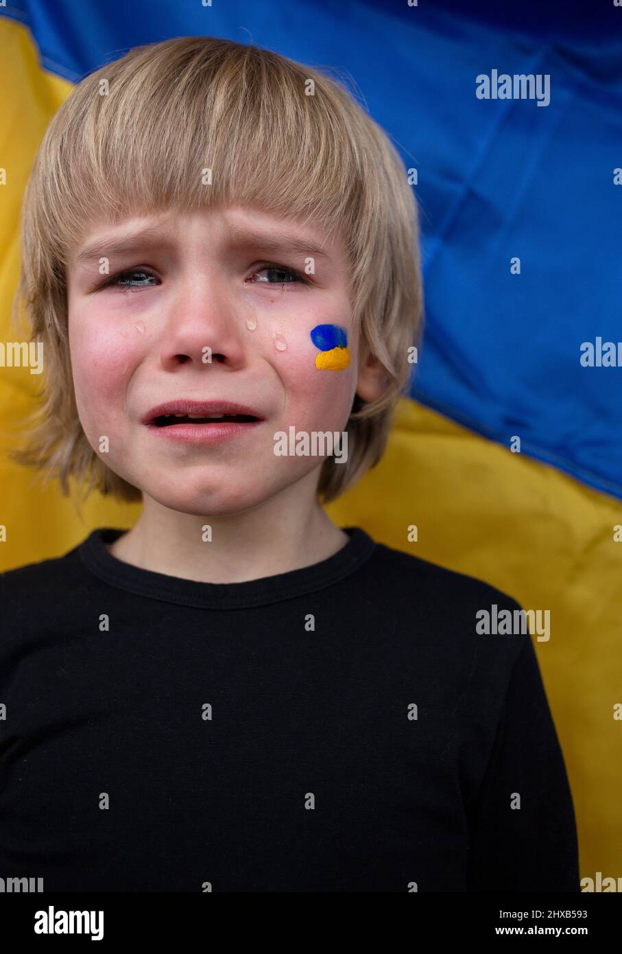 crying frightened boy, against the background of a yellow-blue ...
