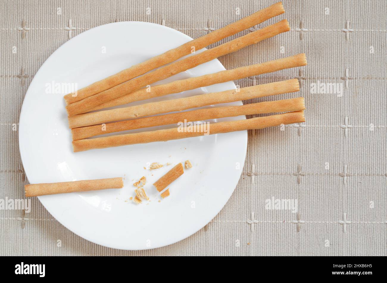 Bread sticks whole and broken on a plate on a fabric background, top ...