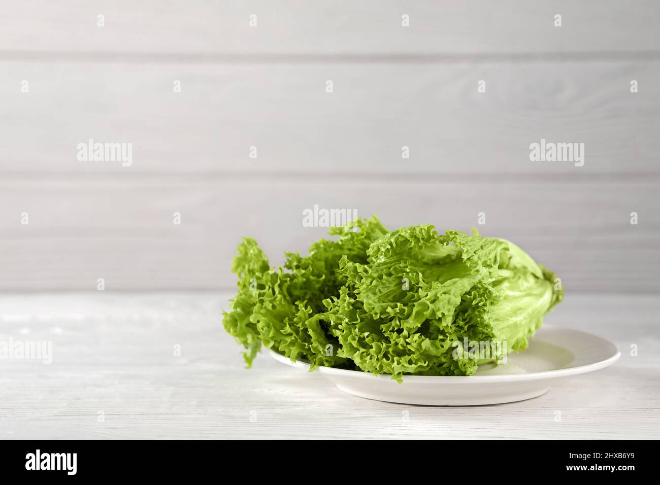 Fresh lettuce leaves on a platter on a wooden background. Dietary ...