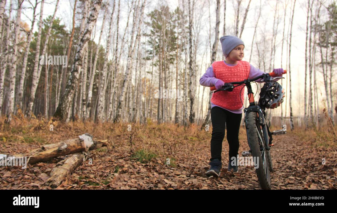 One caucasian children walk with bike in autumn park. Little girl ...