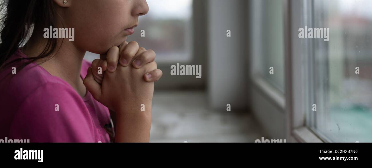 Praying little girl near window Stock Photo - Alamy
