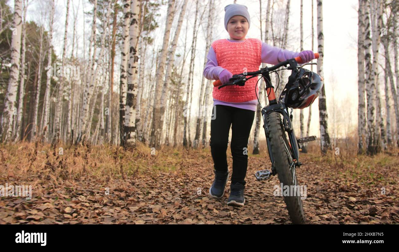 One caucasian children walk with bike in autumn park. Little girl ...