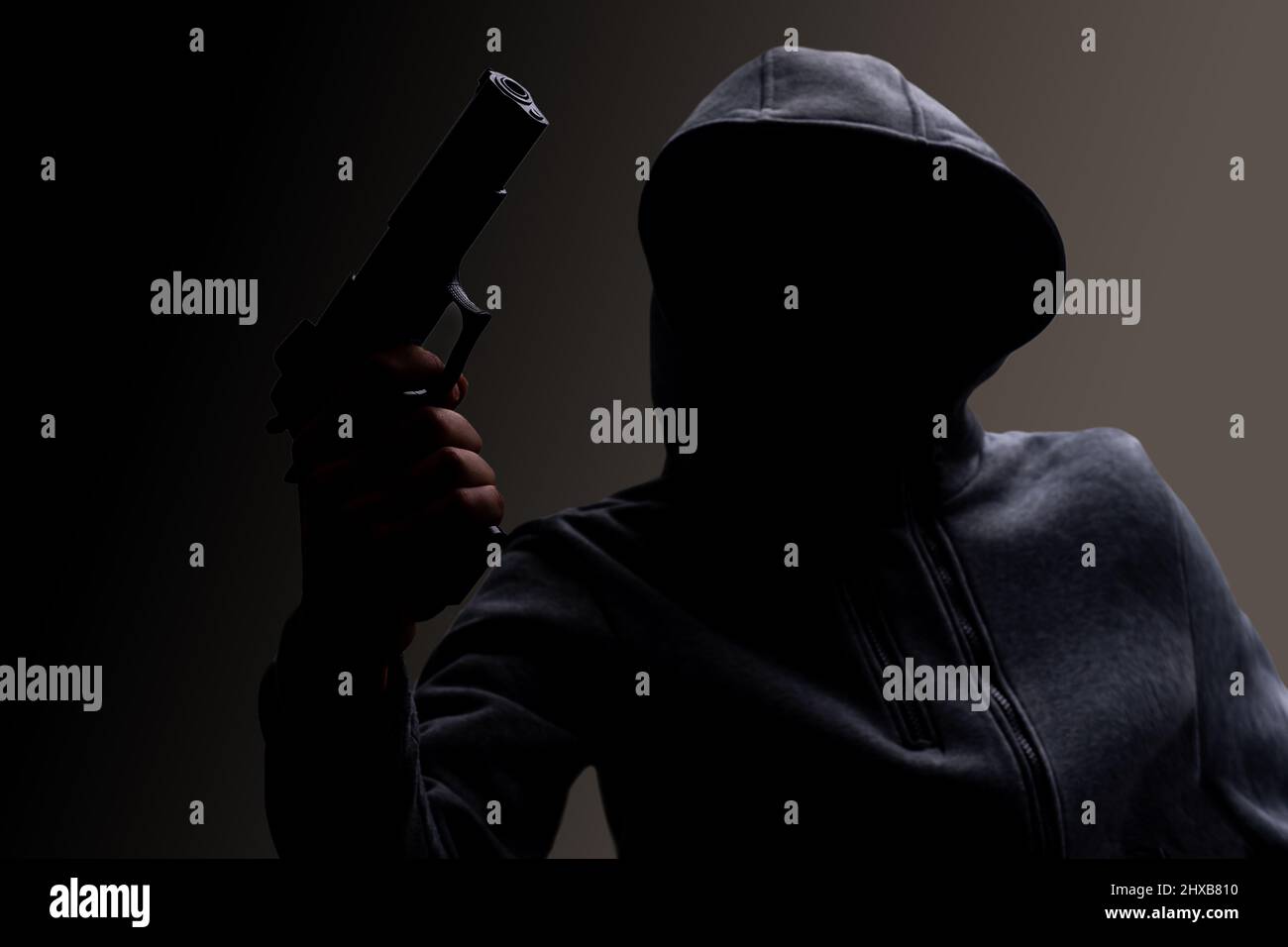 Photo of a creepy horror criminal in black hoodie holding revolver gun ...