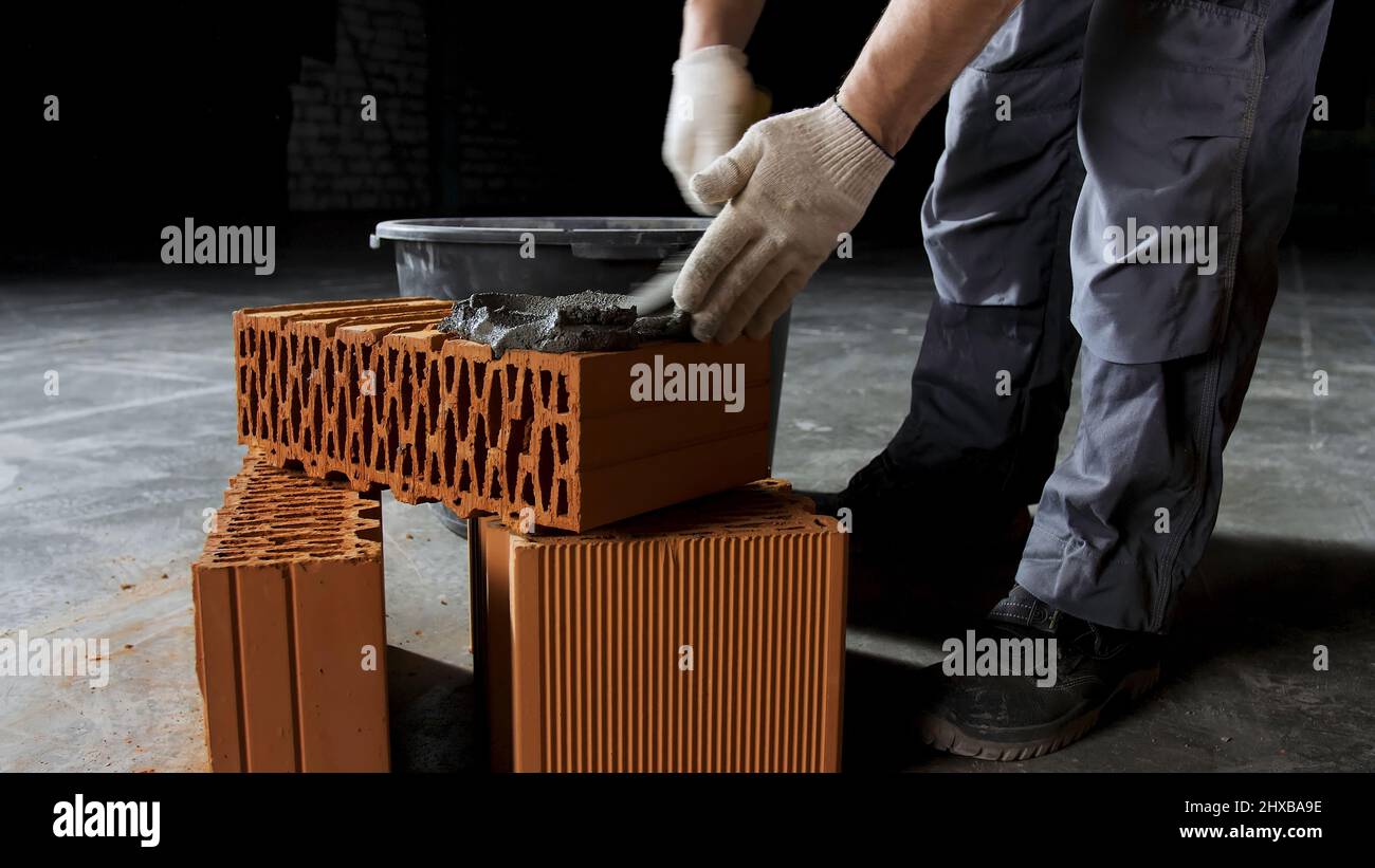Close up of an industrial worker putting cement on the brick for ...