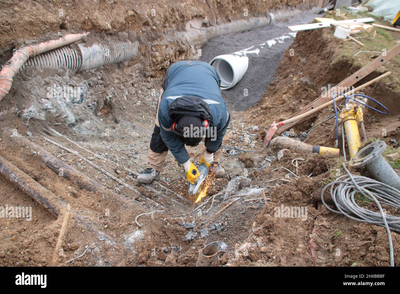Worker in a pit works with an angle grinder Stock Photo - Alamy