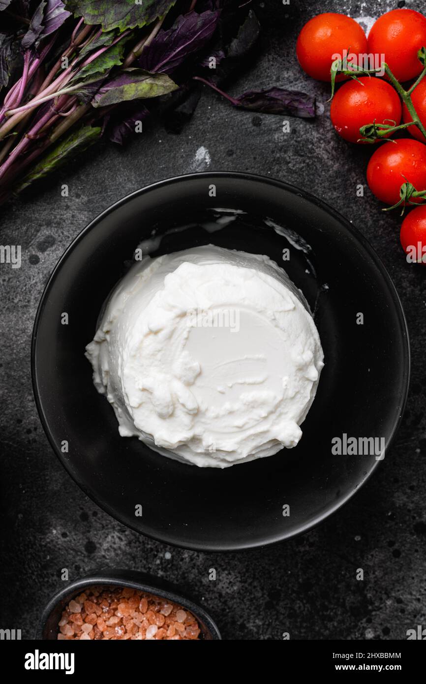 A fresh ricotta set, on black dark stone table background, top view ...
