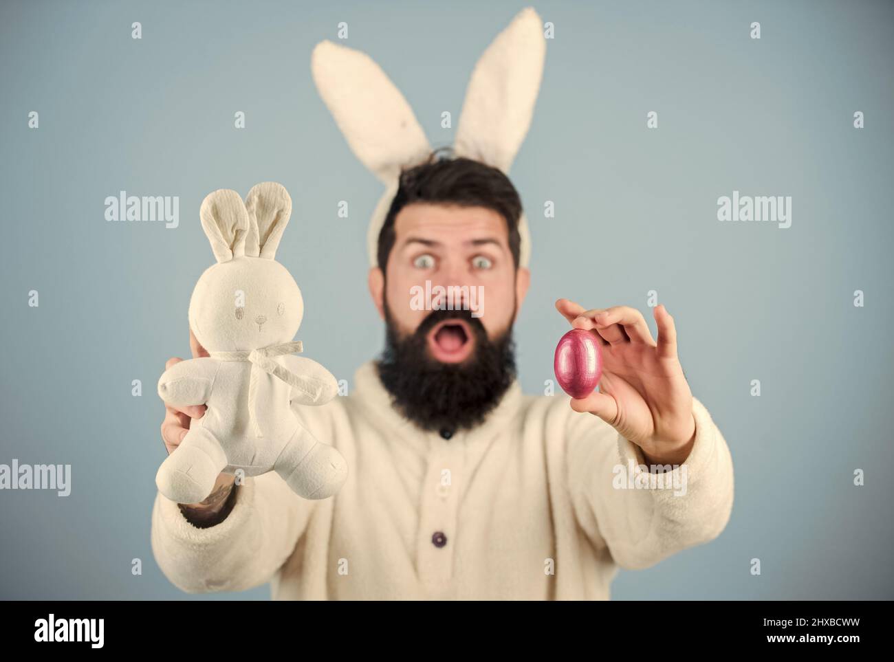 Funny bunny with beard and mustache hold pink egg. Easter symbol ...