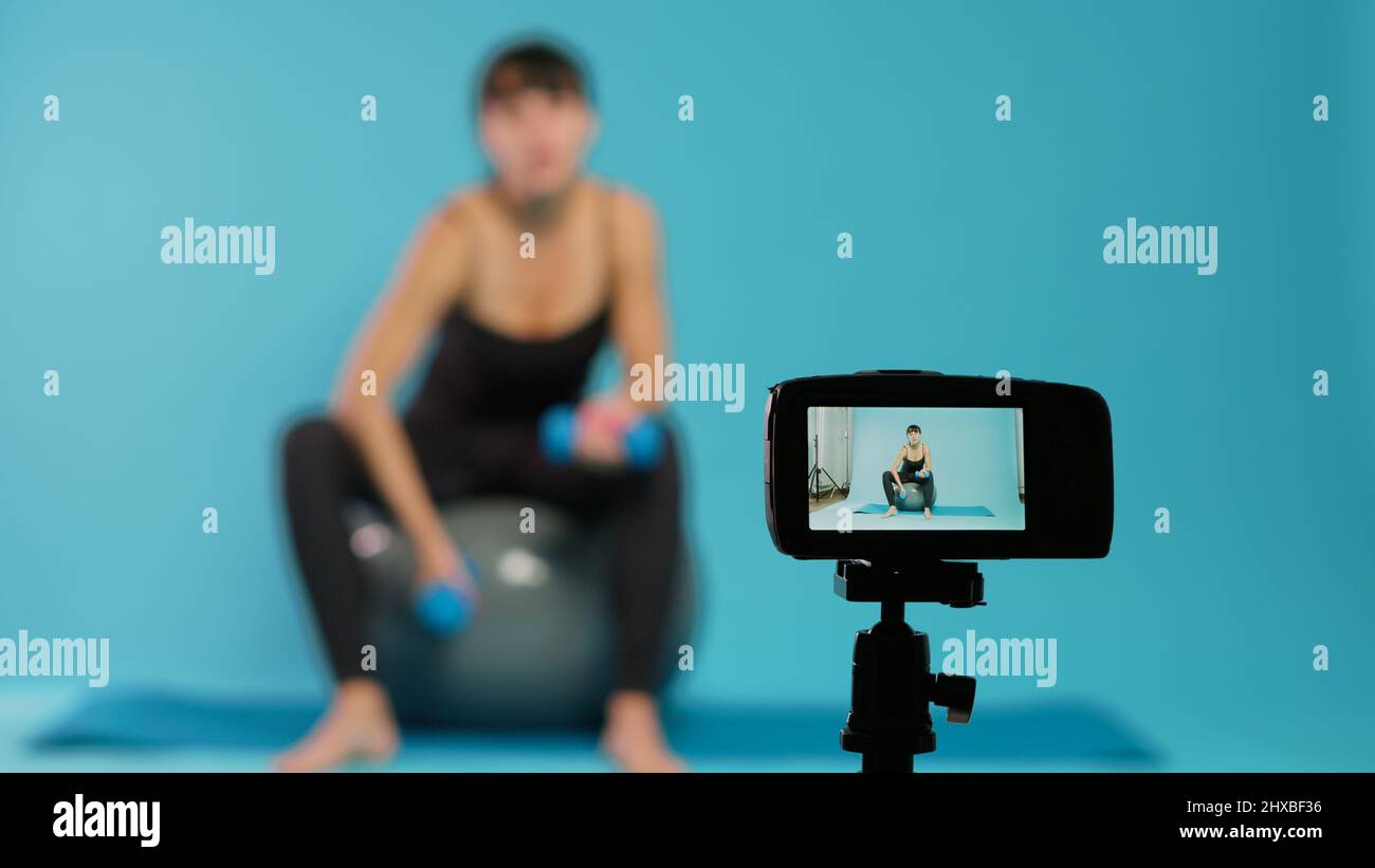 Trainer filming workout video on camera to give fitness advice, using ...