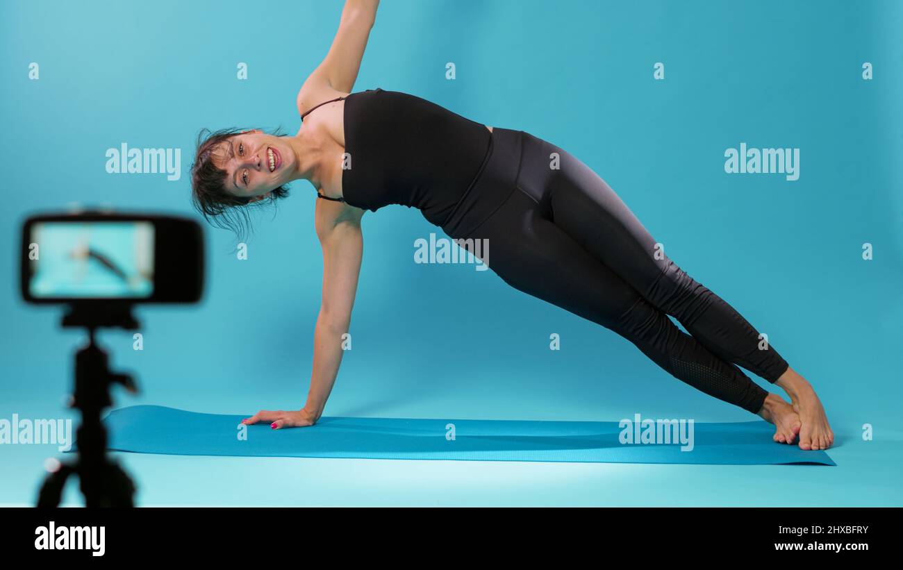 Yoga instructor filming stretching exercise on camera in studio ...