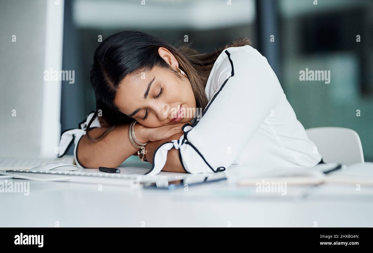Catching a quick snooze. Shot of a young businesswoman sleeping at a ...