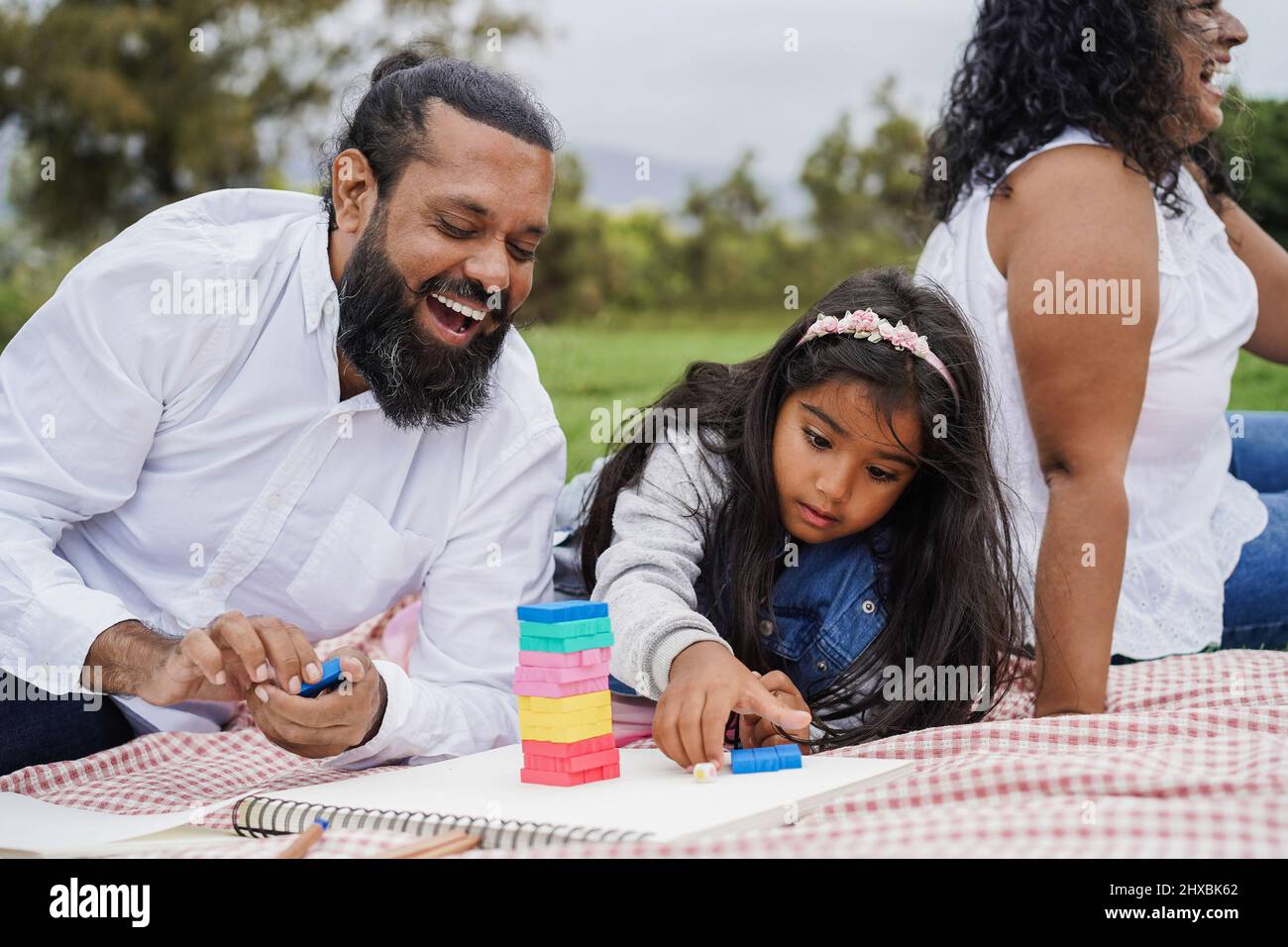 Indian parents having fun at city park playing with wood toys with ...