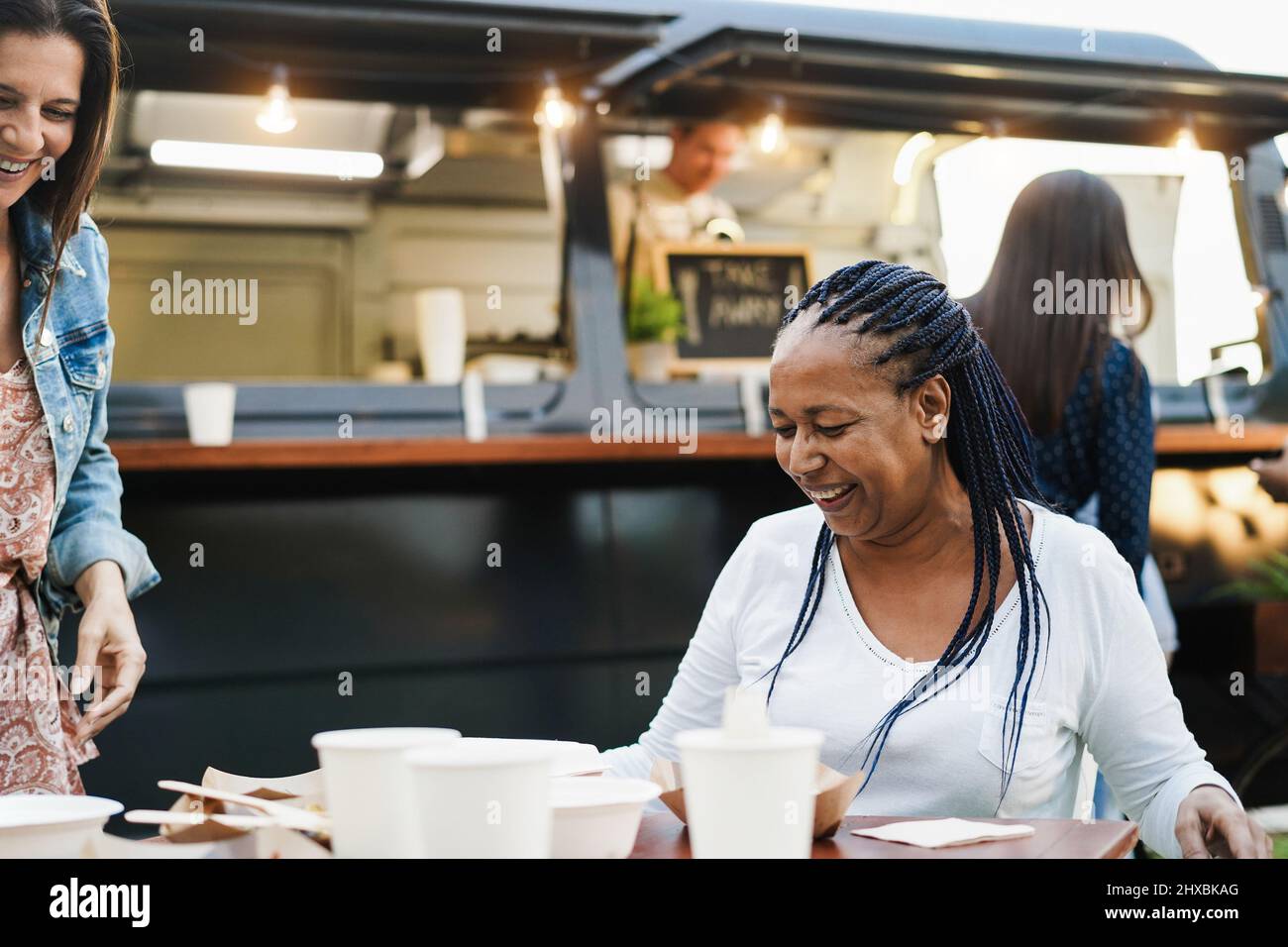 Multiracial women eating at food truck restaurant outdoor - Focus on ...