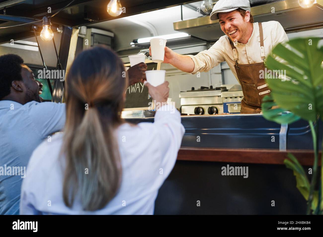 Hispanic man serving take away food inside food truck - Focus on chef ...