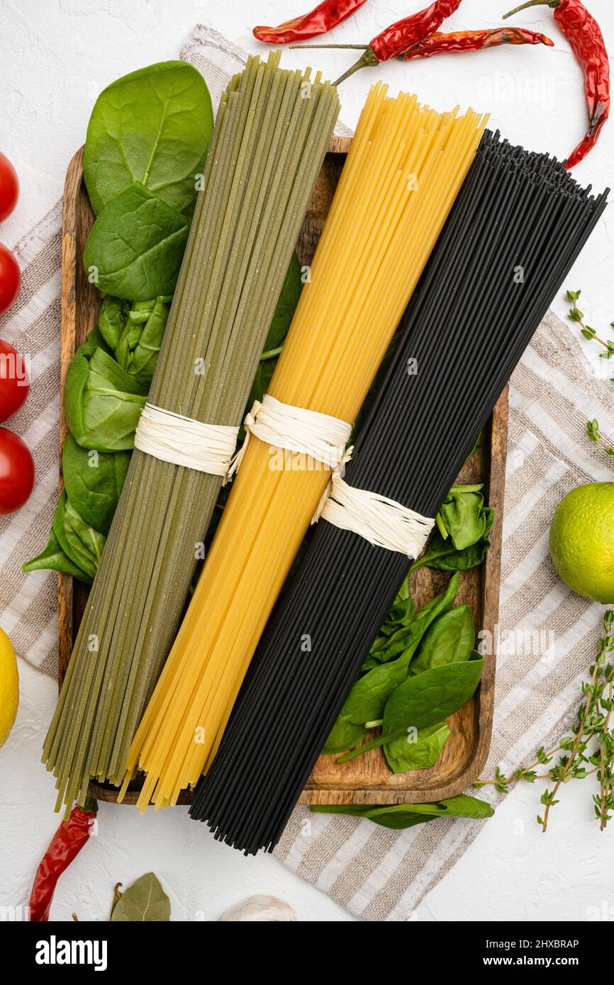 Multi colored spaghetti with ingredients set, on white stone table ...