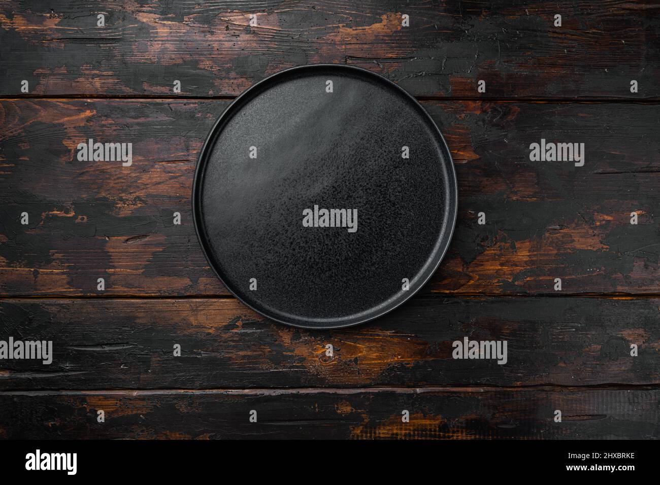 Black plate set, on old dark wooden table background Stock Photo - Alamy