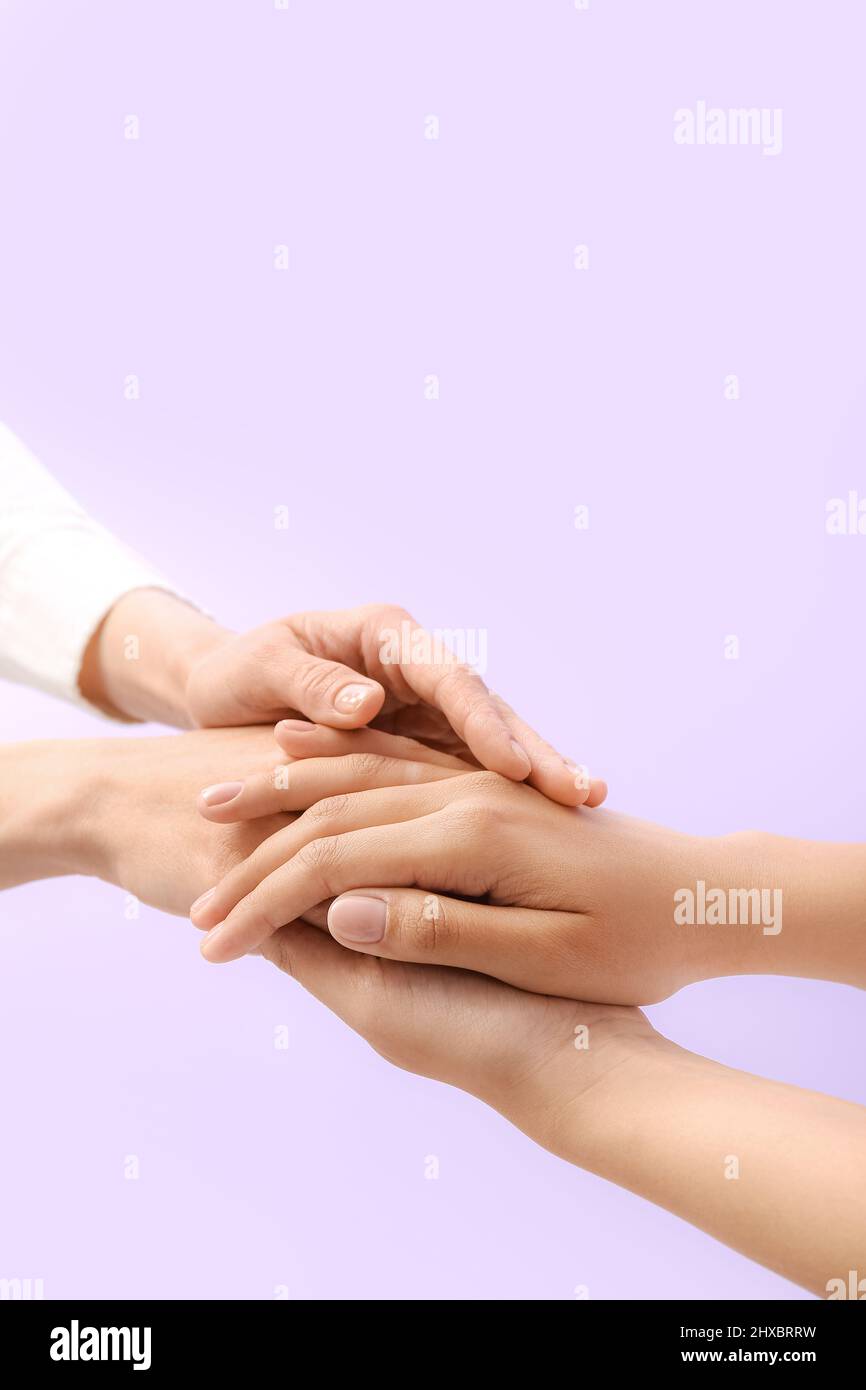 Women holding hands together on color background Stock Photo - Alamy
