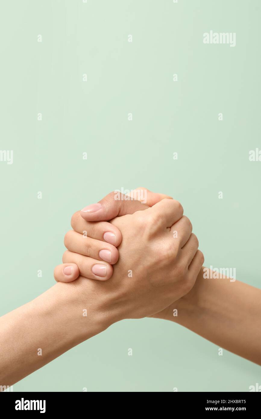 Women holding hands together on color background Stock Photo - Alamy