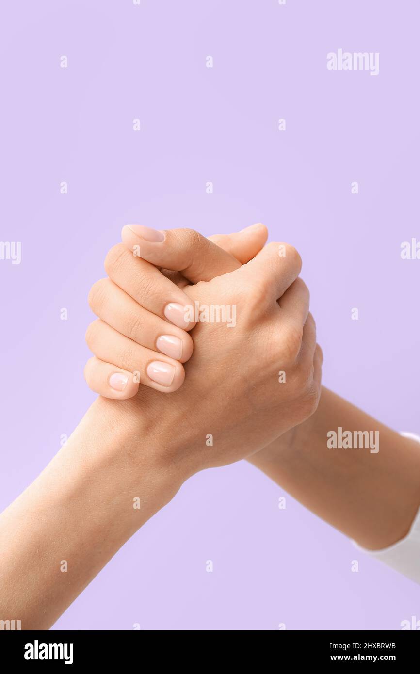 Women holding hands together on color background Stock Photo - Alamy