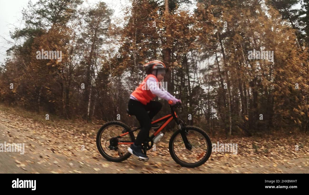 One caucasian children rides bike road in autumn park. Little girl ...