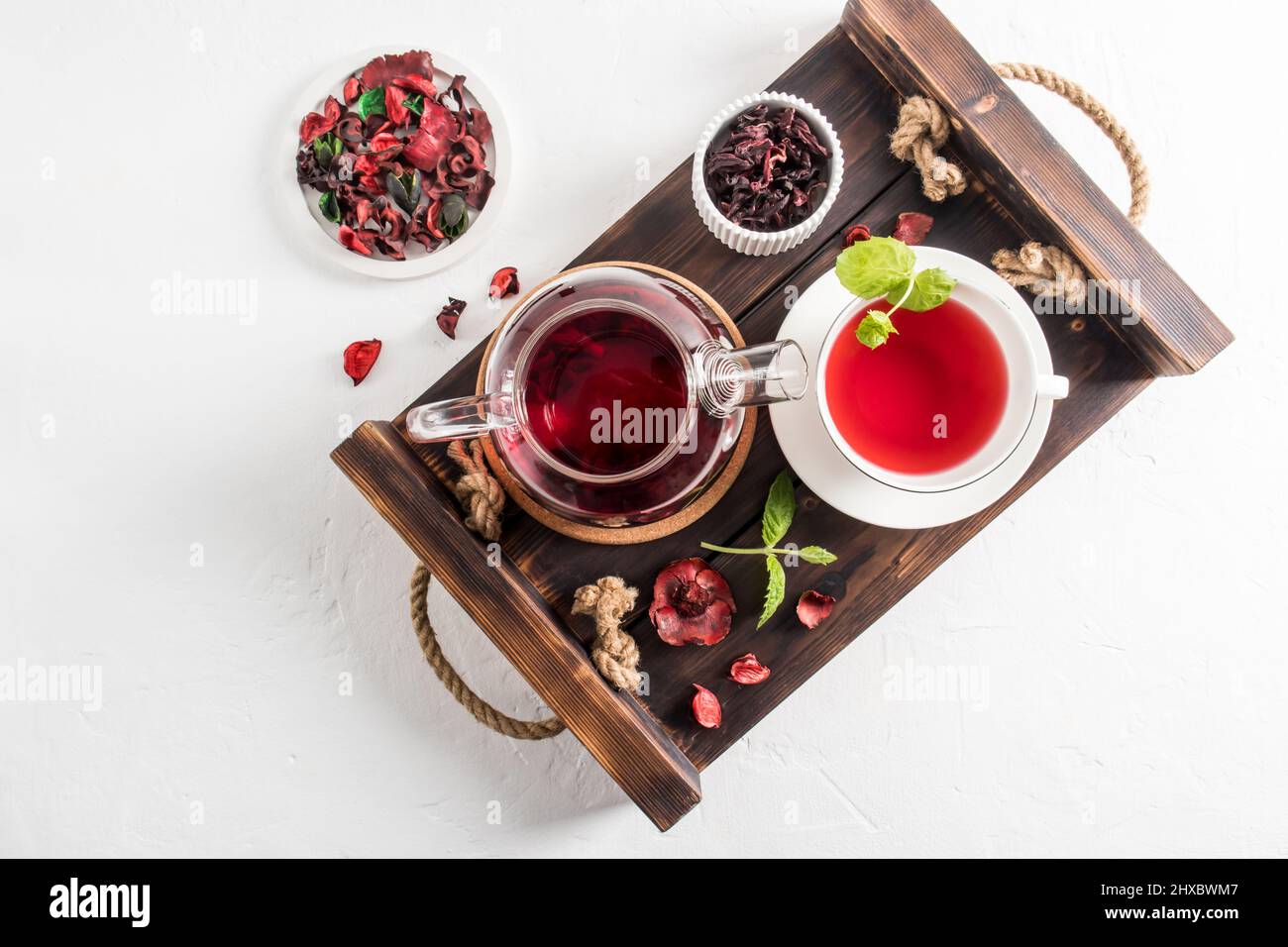 teapot of fragrant tea petals rose hibiscus and mint on a wooden tray ...