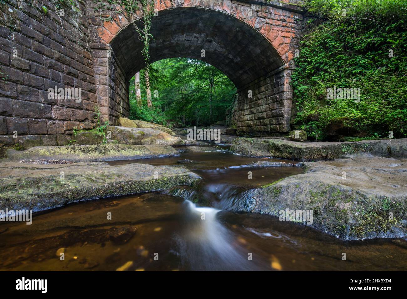 Small red brick bridge over the stream at falling foss waterfall. Small ...