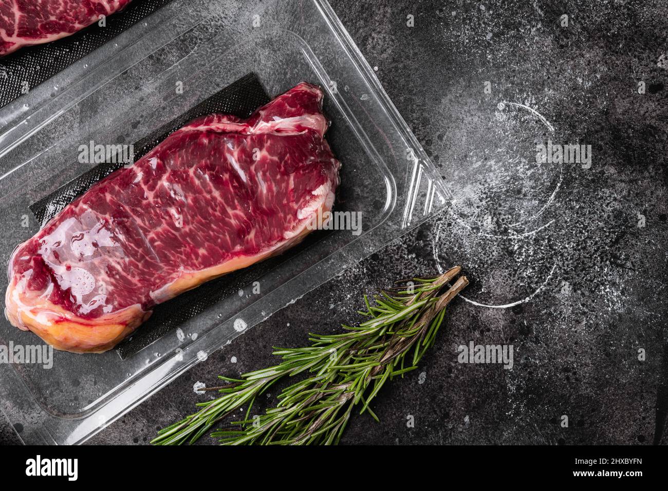 Raw marbled beef steaks in vacuum pack, on black dark stone table ...