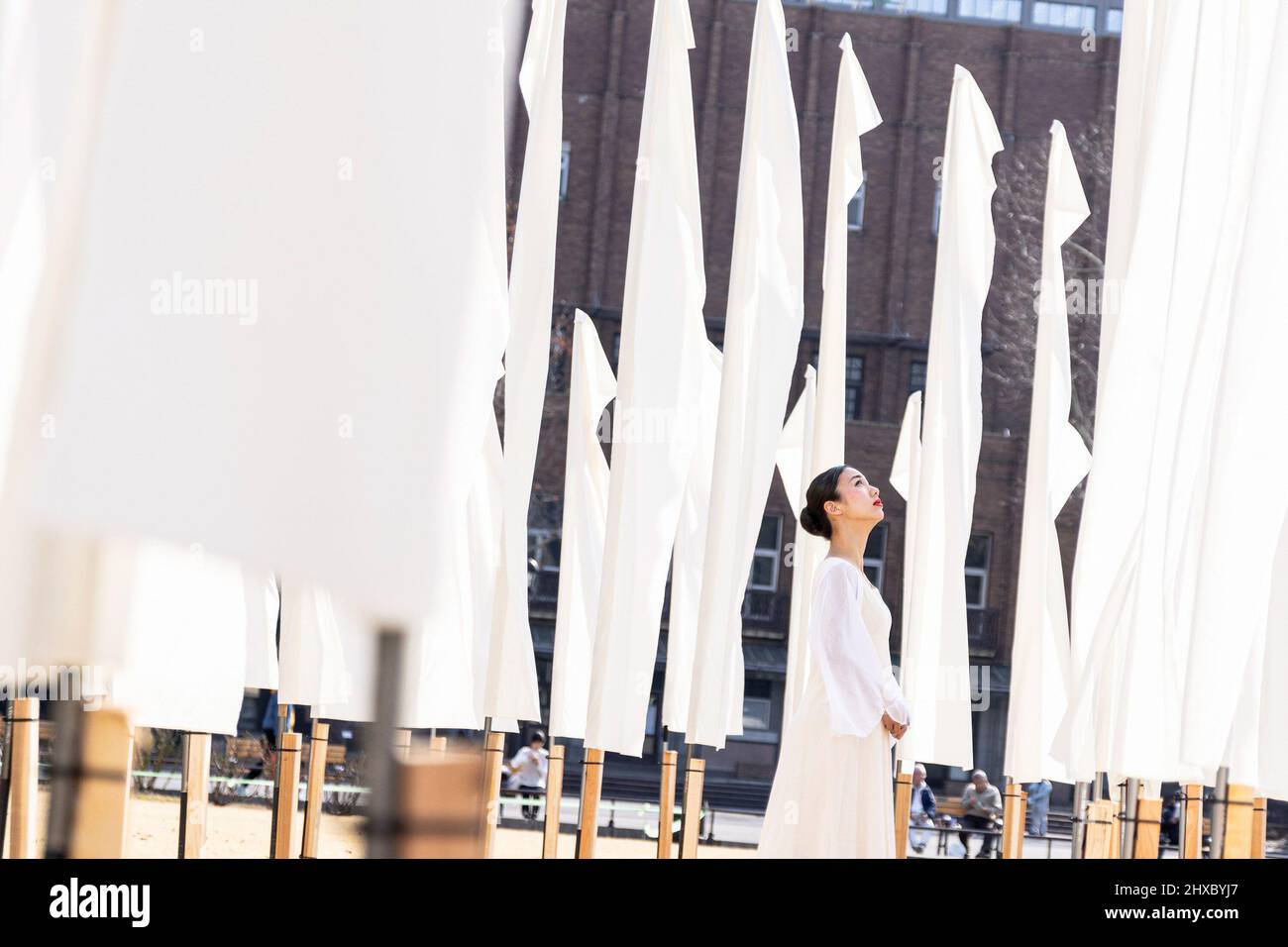 A dancer stands amidst white flags during the memorial event at Hibiya ...