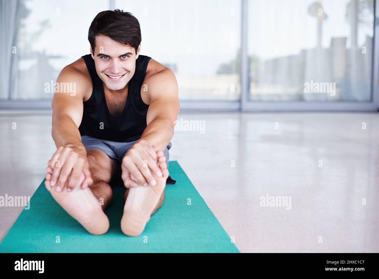 I can touch my toes. A portrait of a happy young man stretching on an ...