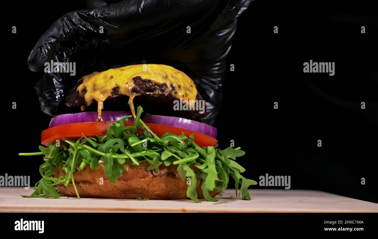 Craft burger is cooking on black background. Consist: sauce, arugula ...