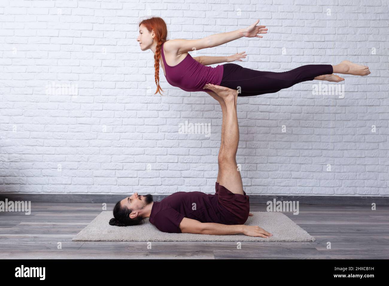 Young couple having fun at home with some acro yoga poses in different ...