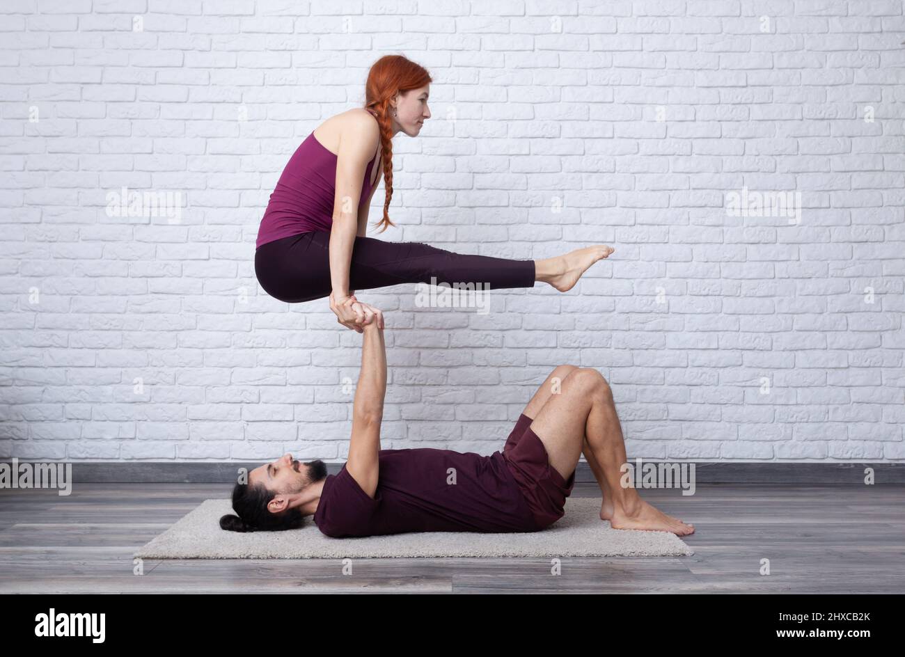 Young couple having fun at home with some acro yoga poses in different ...