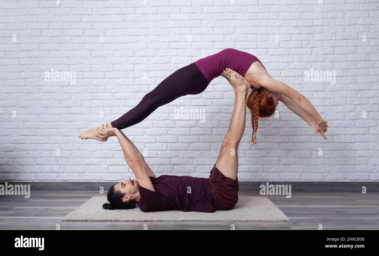 Young couple having fun at home with some acro yoga poses in different ...