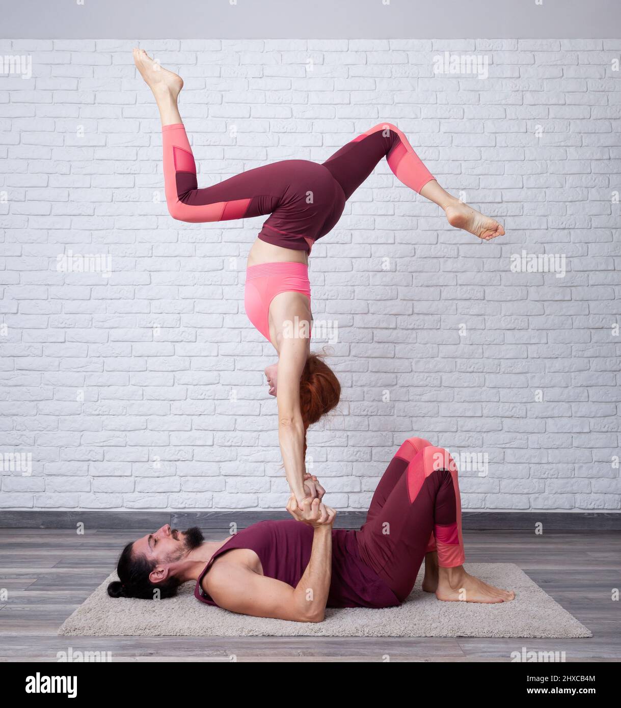 Young couple having fun at home with some acro yoga hand to hand with ...