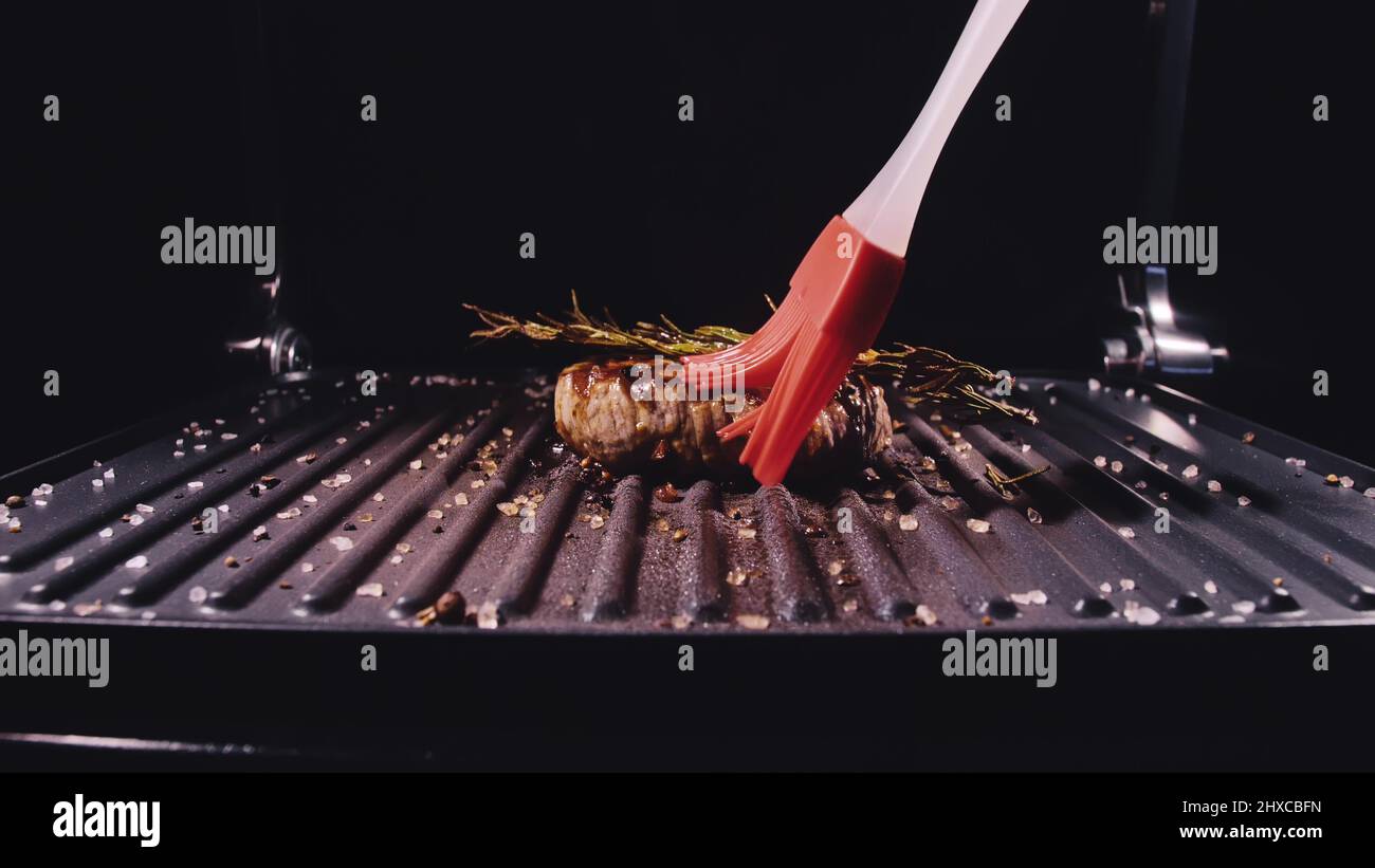 Delicious juicy meat steak cooking on grill. Silicone cooking brush ...