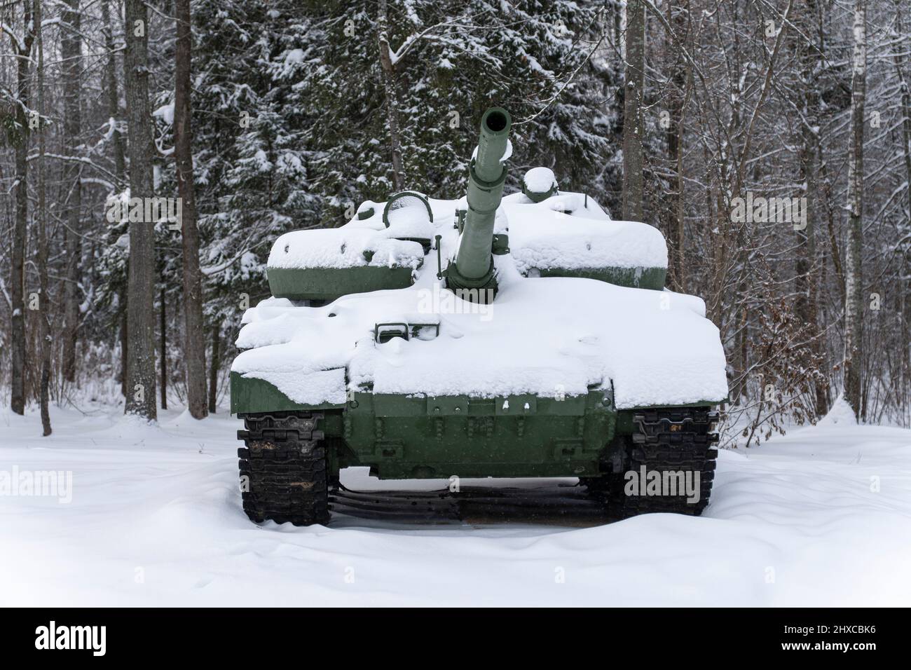 A disguised tank under the snow rides among the trees in the forest ...